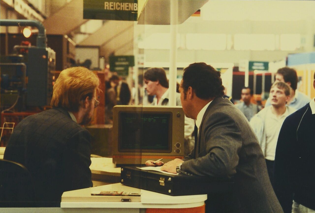 Zwei Männer werden von hinten gezeigt wie sie auf einen Computer ...