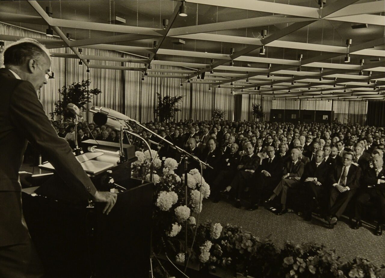 Emo 1977 Pressekonferenz Links Steht Ein Mann Auf Der Bühne Am Pult In Der Rechten Bilhälfte